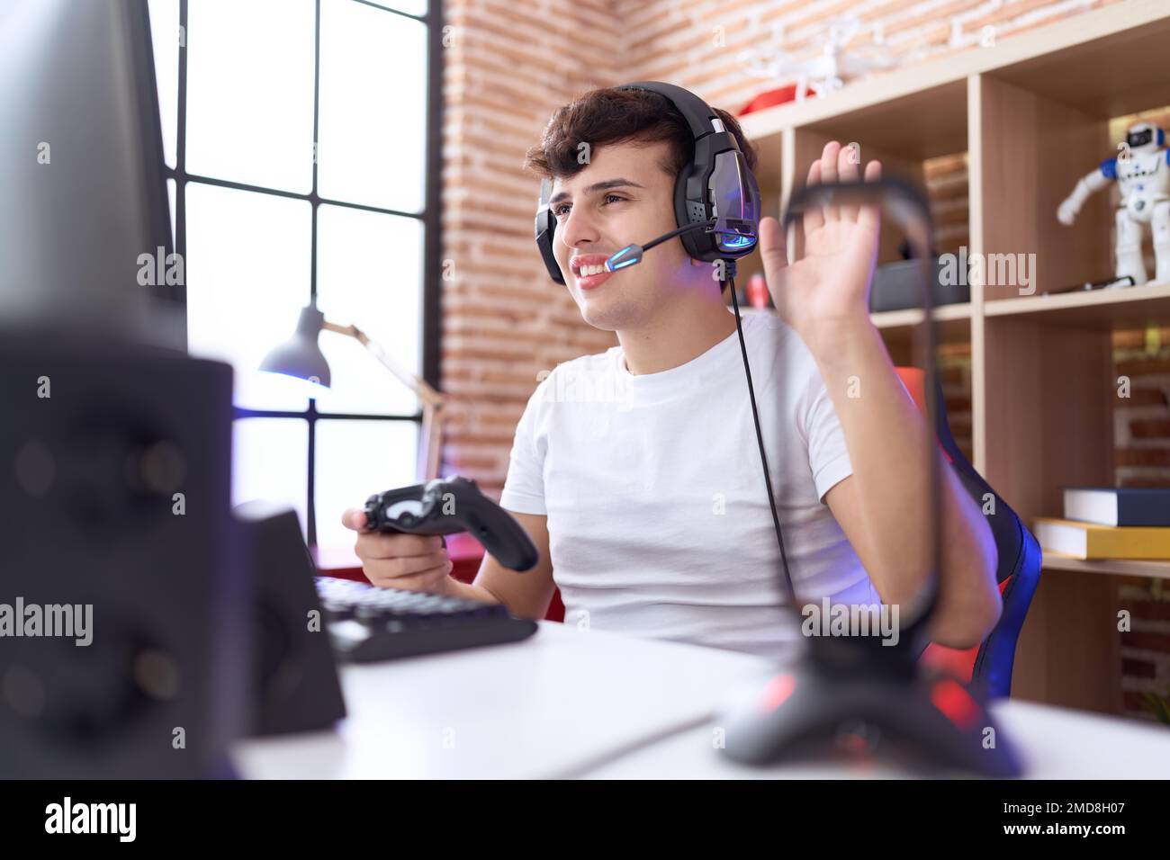 Non binary man streamer playing video game using joystick at gaming ...