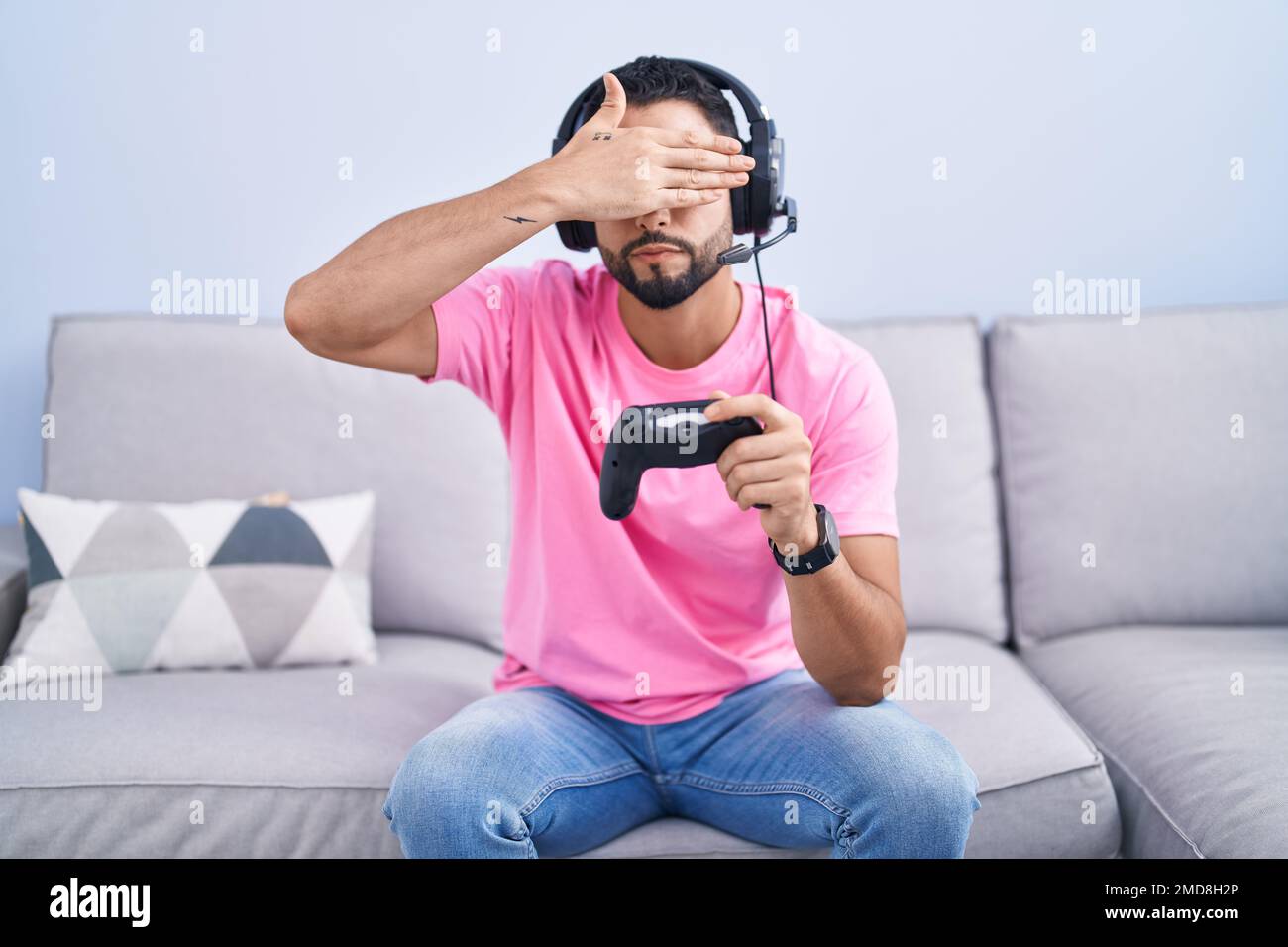 Hispanic young man playing video game holding controller sitting on the ...
