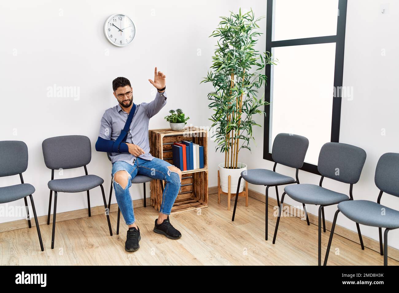 Young arab man suffering sitting on chair with arm sling and finger ...