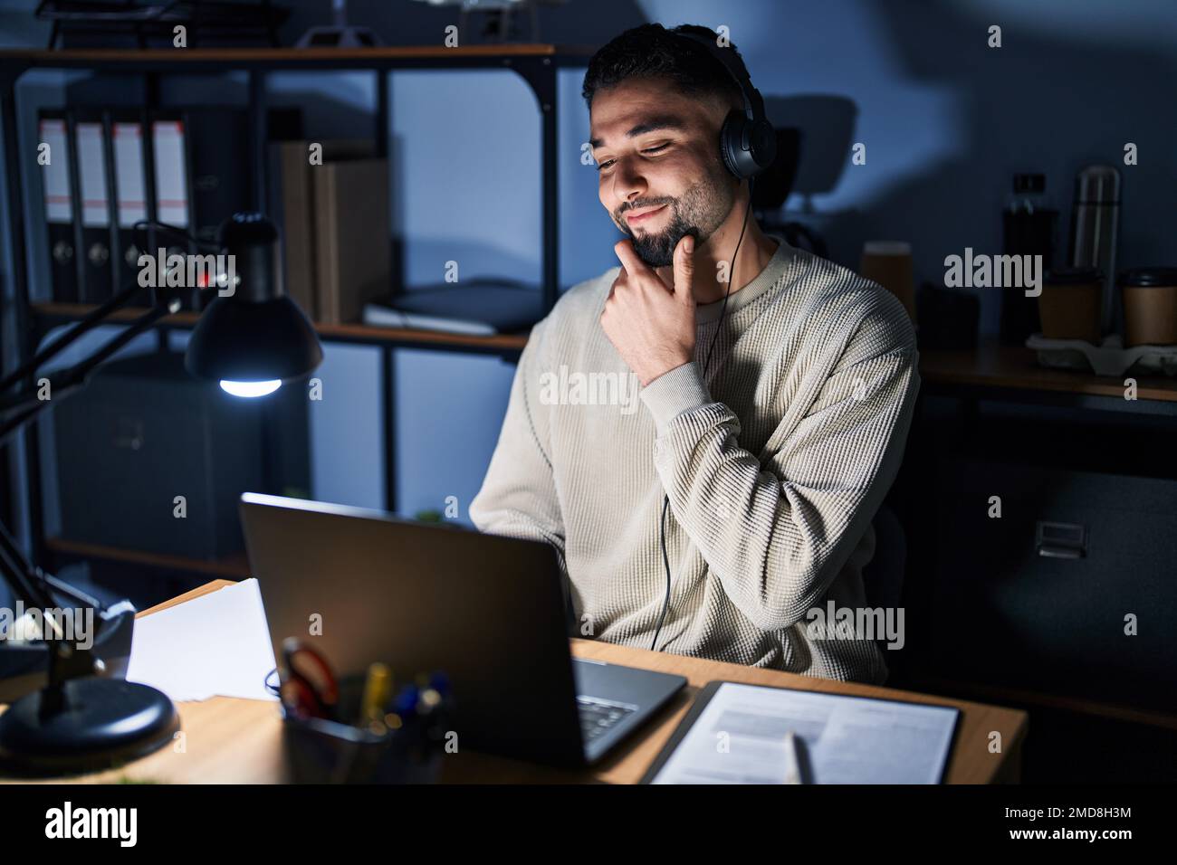 Young handsome man working using computer laptop at night looking ...