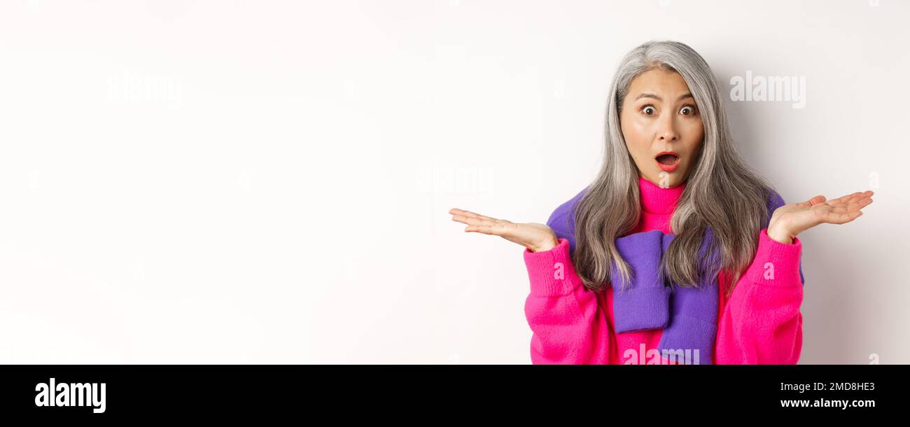 Close up of shocked asian mom staring at camera, spread hands sideways ...