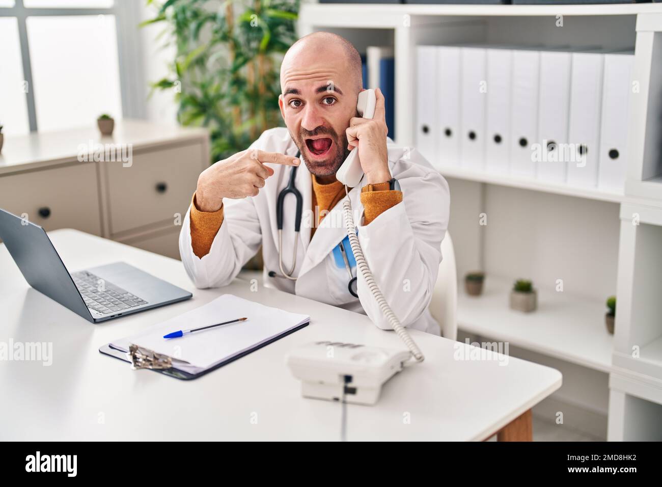 Young bald man with beard working on telephone appointment smiling ...