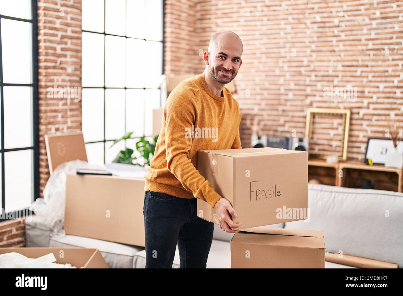 Young man smiling confident holding fragile cardboard box at new home Stock Photo - Alamy