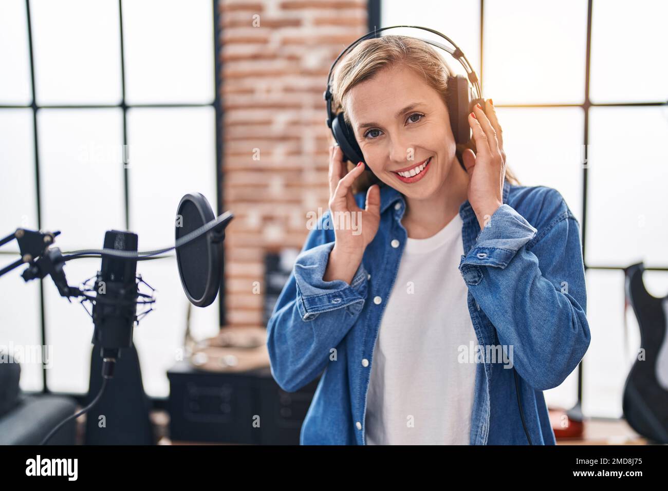 Young blonde woman musician smiling confident sitting on table at music ...