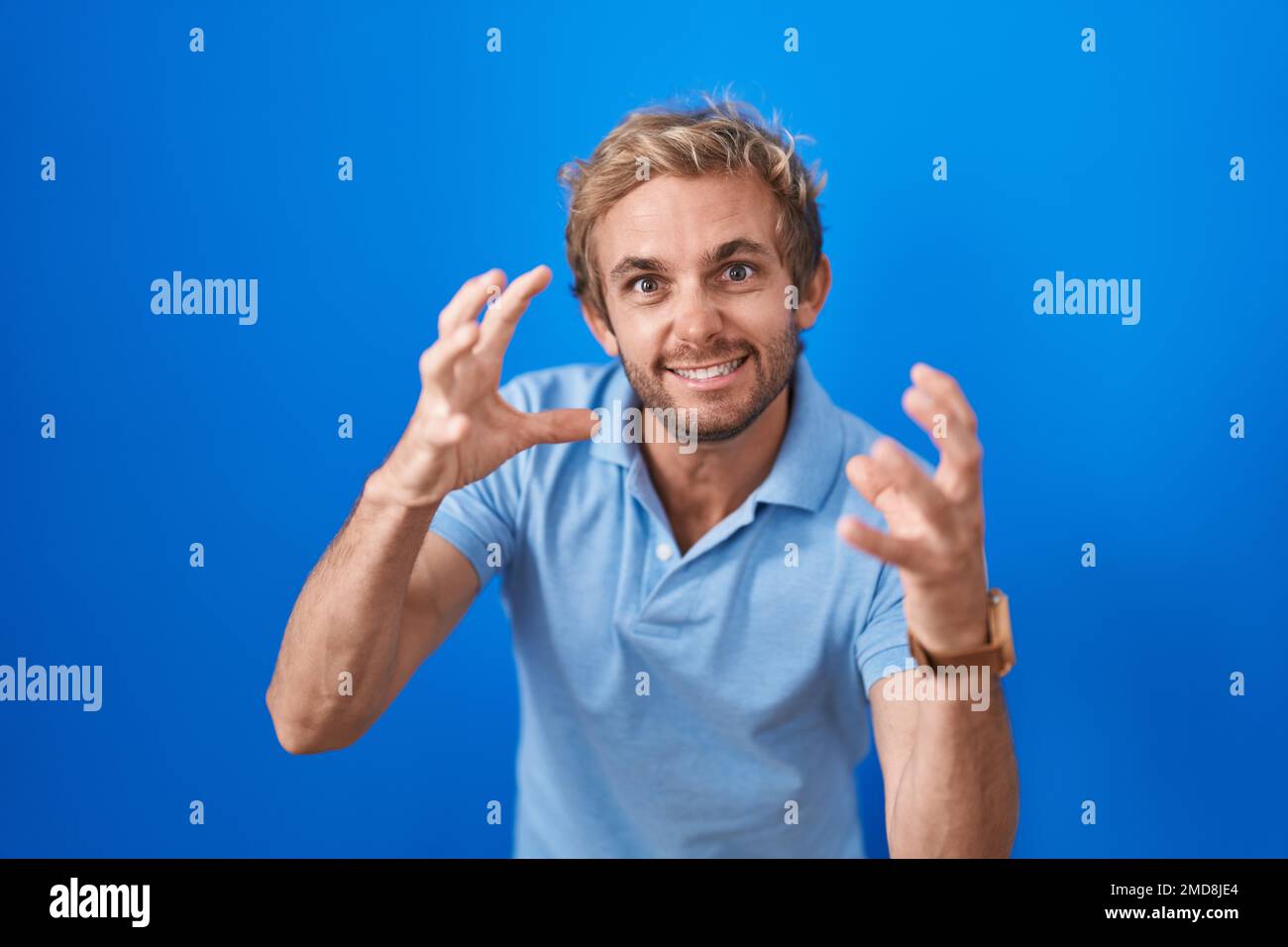 Caucasian man standing over blue background shouting frustrated with ...