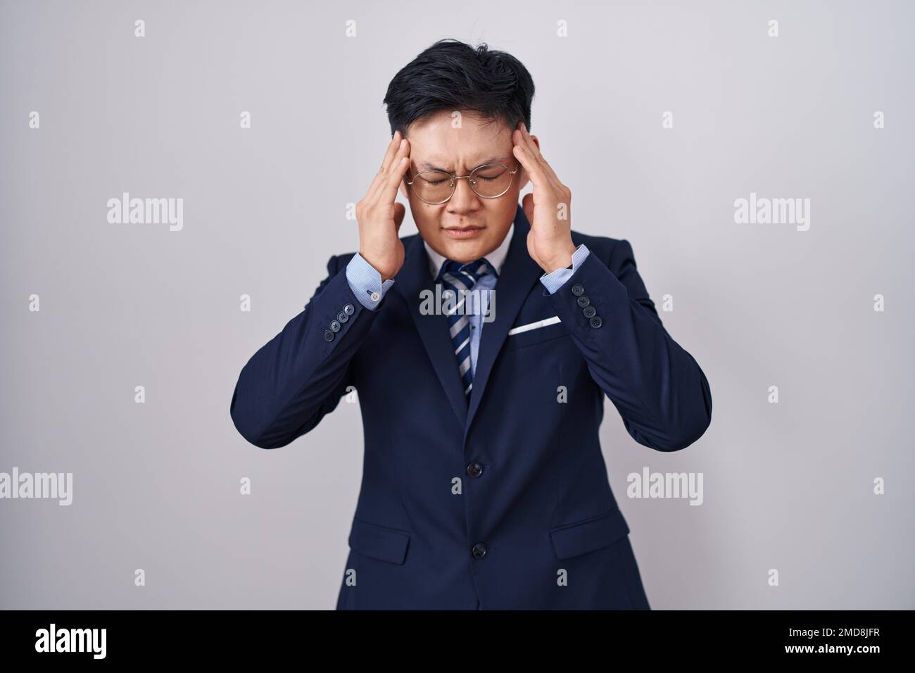 Young asian man wearing business suit and tie with hand on head ...