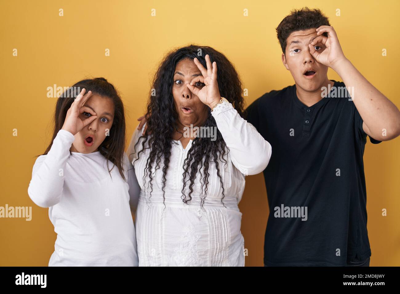 Family of mother, daughter and son standing over yellow background ...