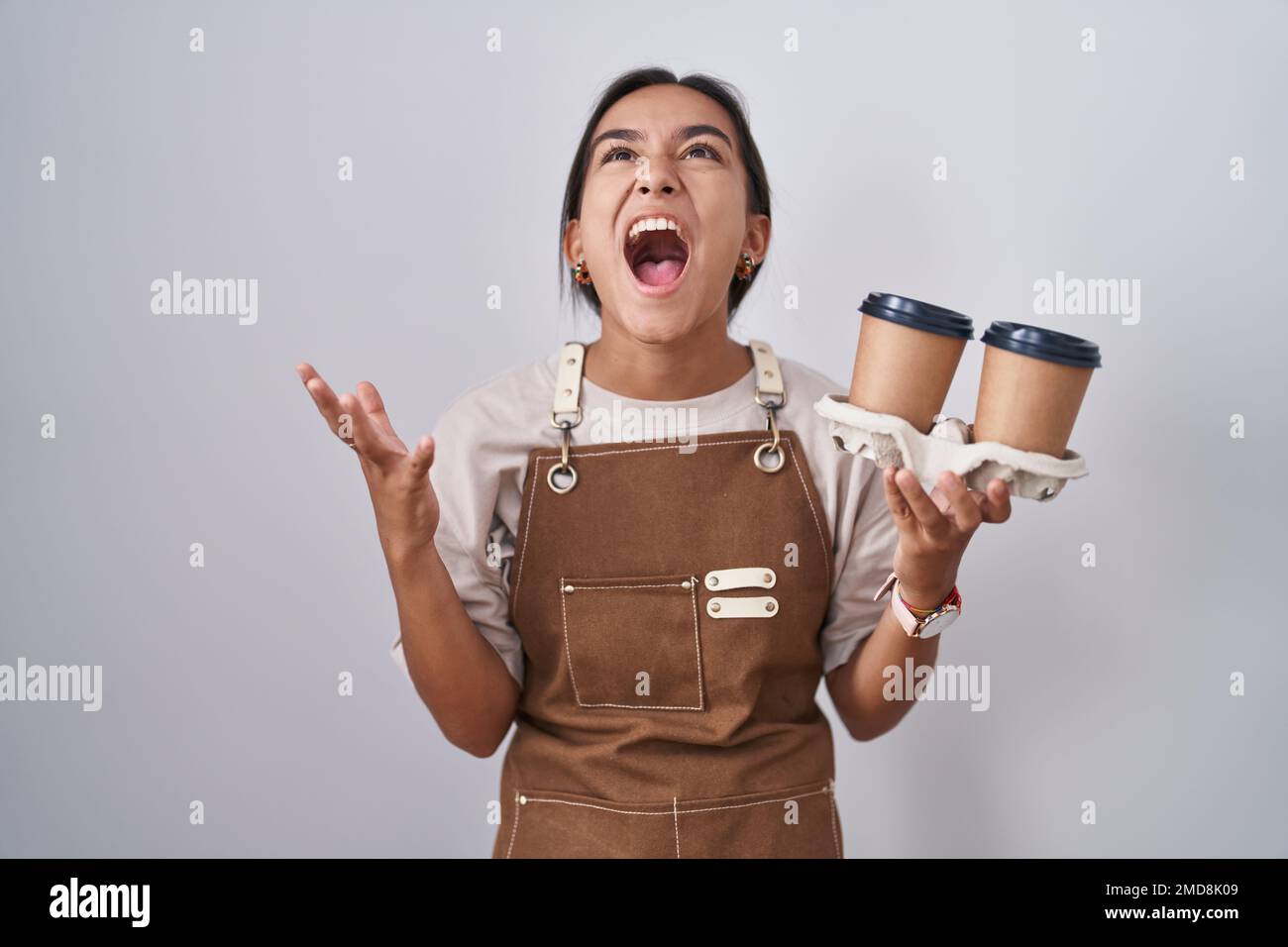 Young hispanic woman wearing professional waitress apron holding coffee ...