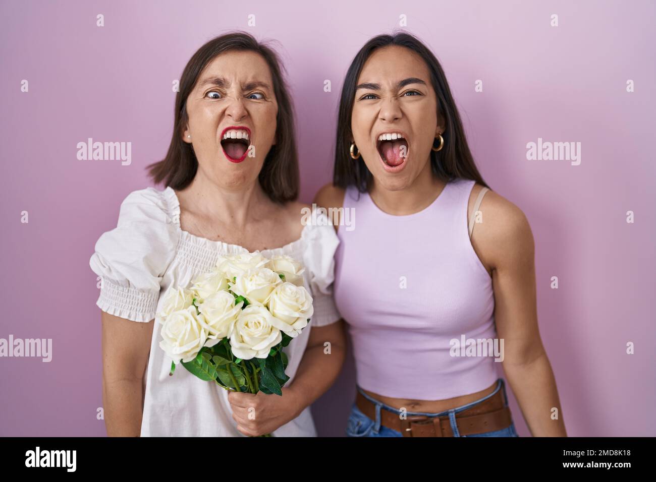 Hispanic mother and daughter holding bouquet of white flowers angry and ...