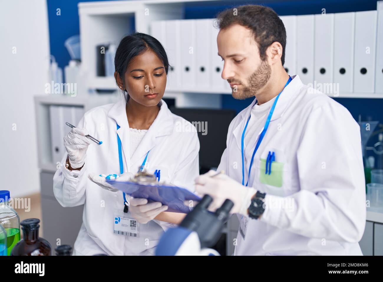 Man and woman scientists holding capsule writing report at laboratory ...