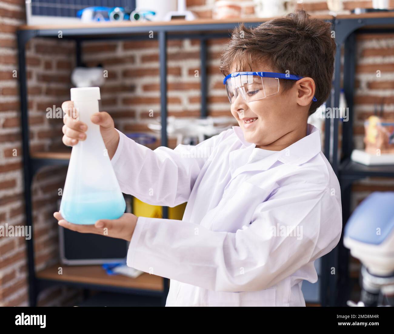 Adorable hispanic boy student smiling confident holding test tube at ...