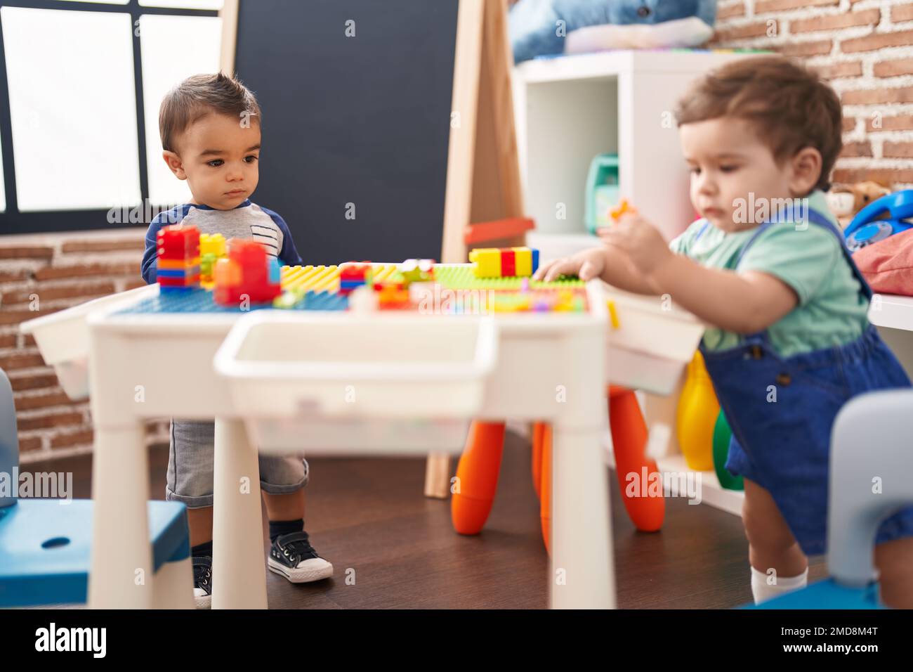 Two kids playing with construction blocks standing at kindergarten ...