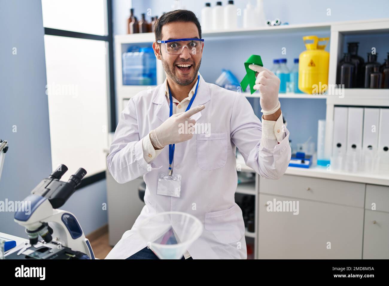 Young hispanic man with beard working at scientist laboratory holding ...