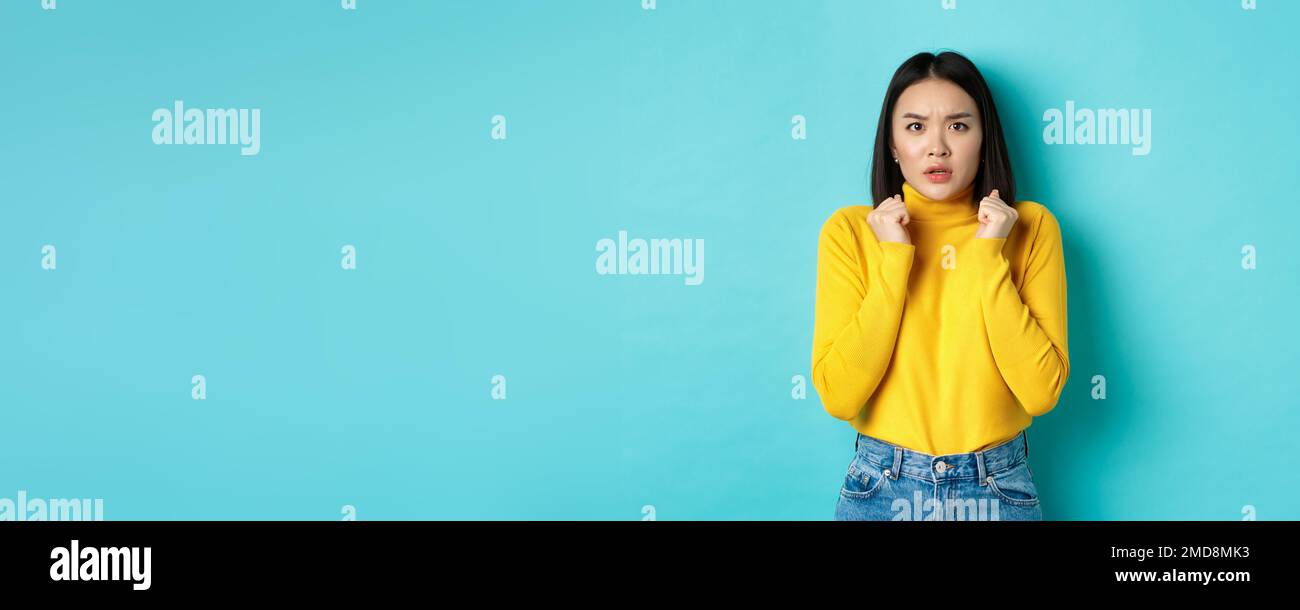 Image of worried asian woman with short dark hair, clench hands and ...