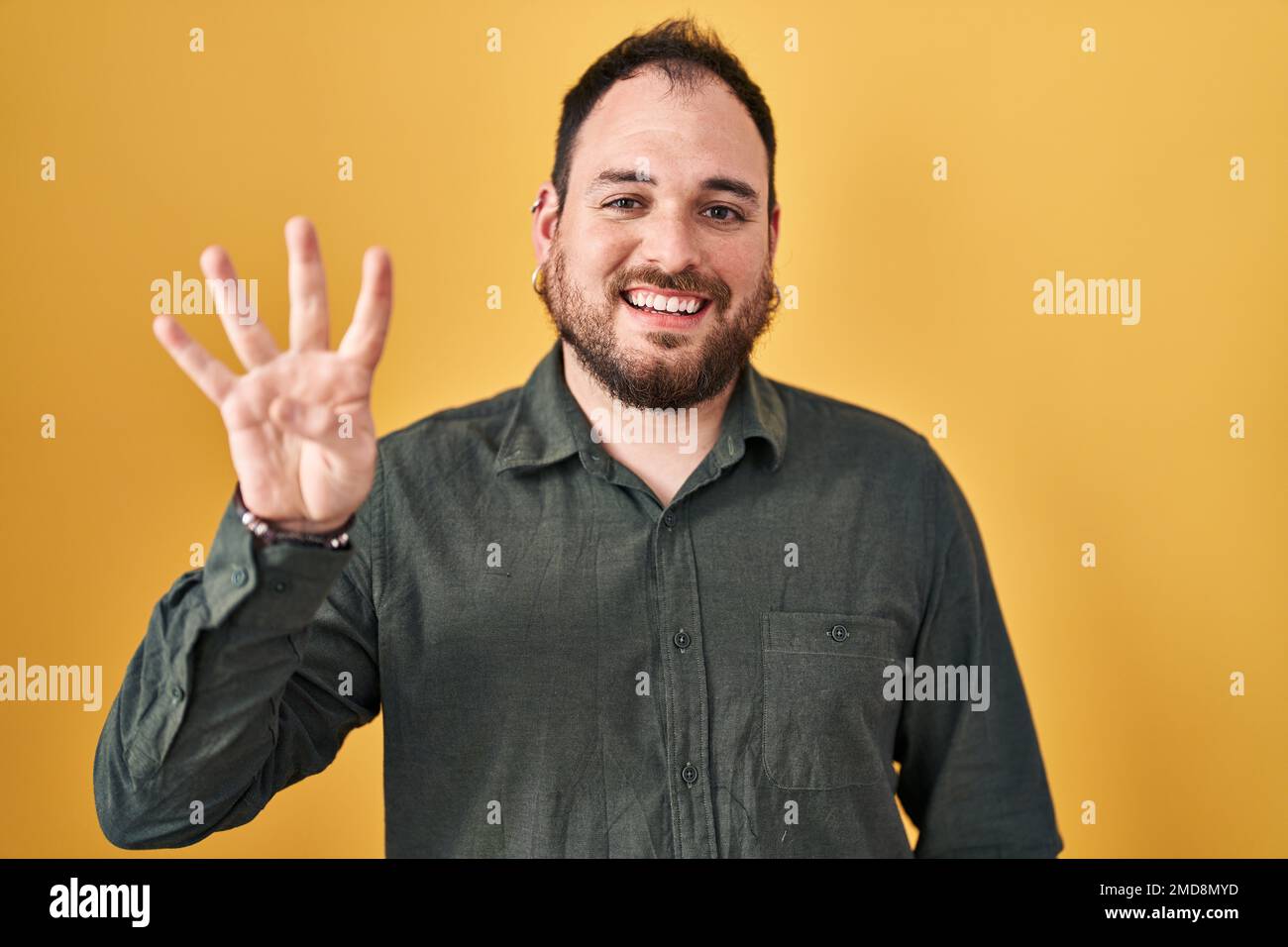 Plus size hispanic man with beard standing over yellow background ...