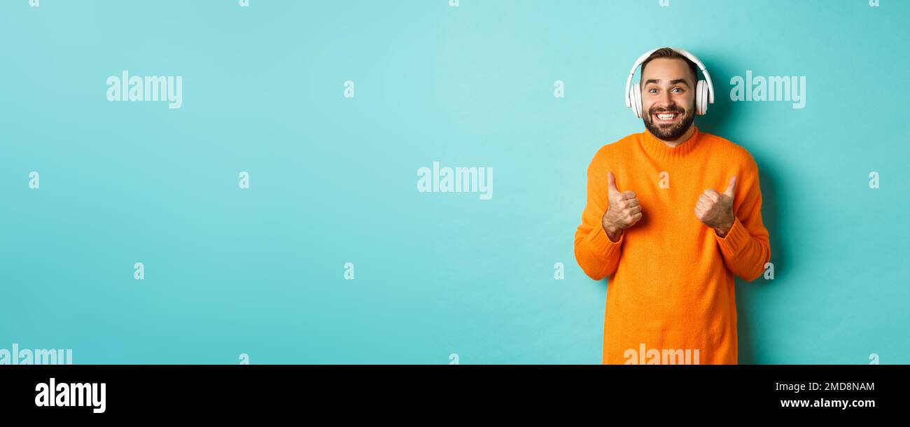 Amazed adult man listening music in headphones, looking at camera ...
