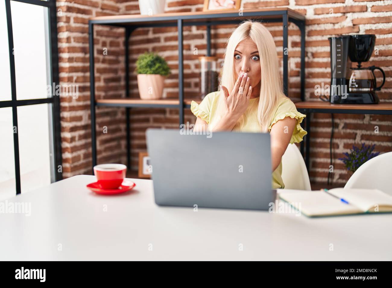 Caucasian woman doing video call with laptop covering mouth with hand ...