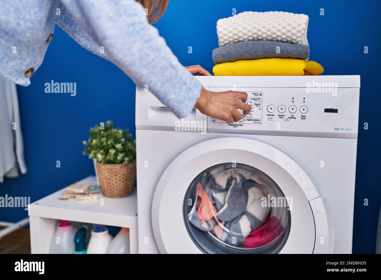 Young woman turning on washing machine at laundry room Stock Photo - Alamy