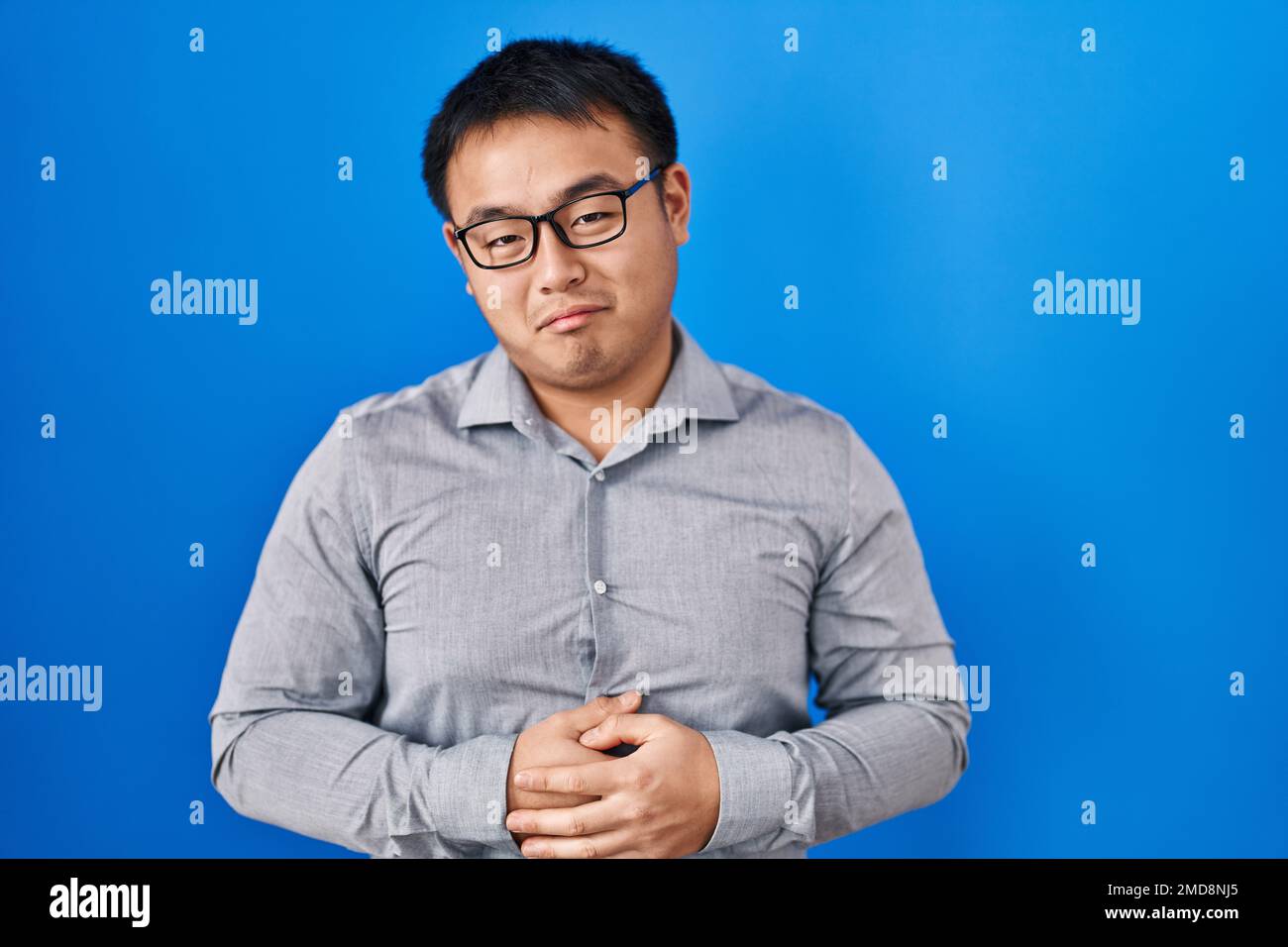 Young chinese man standing over blue background depressed and worry for ...
