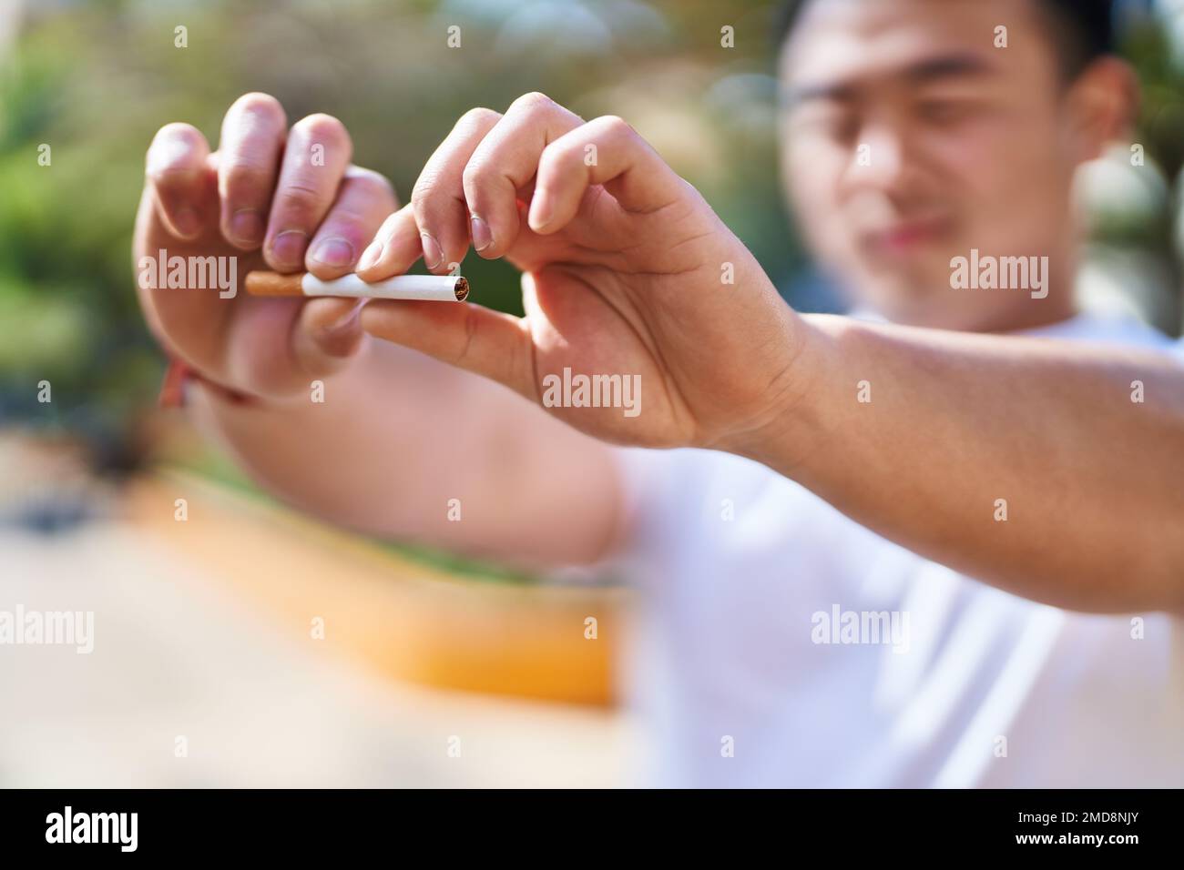 Young chinese man breaking cigarette at park Stock Photo - Alamy