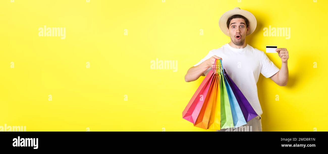Impressed man showing shopping bags with products and credit card ...