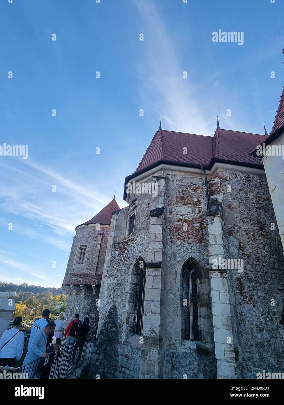 A low-angle vertial shot of the Poenari Citadel and people beside it in ...