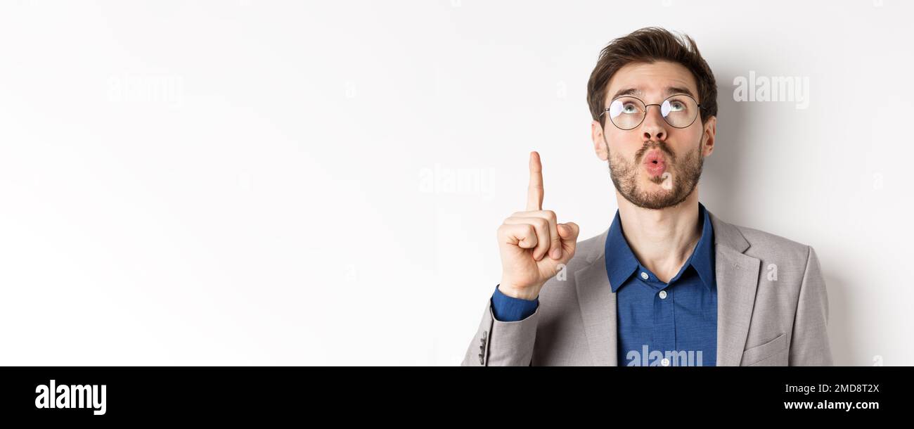 Excited handsome man in glasses and business suit, look up and pointing ...