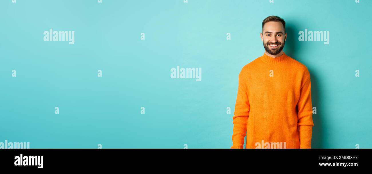 Lifestyle. Handsome man in orange sweater smiling at camera, happy face ...