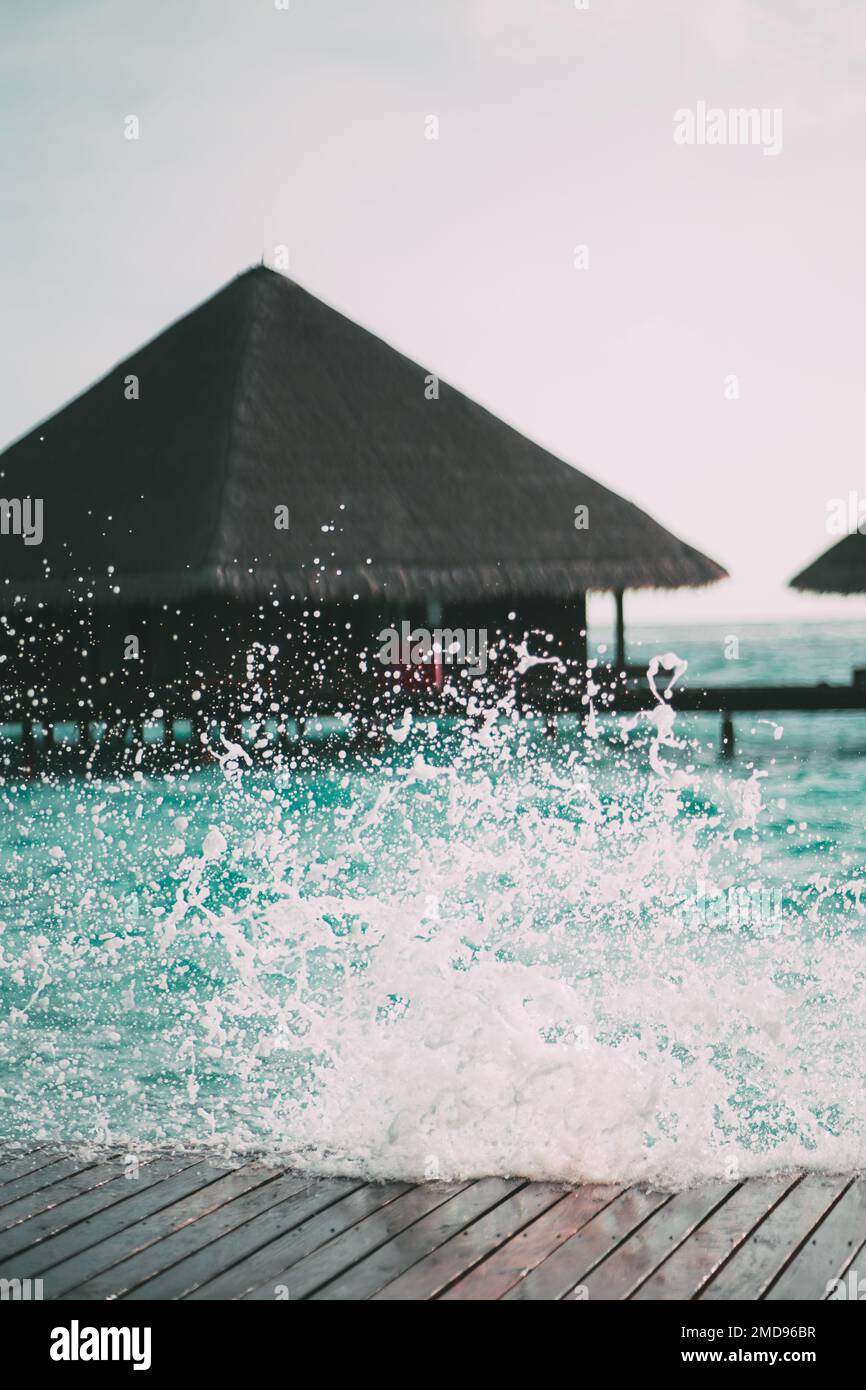 A vertical shot of the seawater splashing against the boardwalk in a ...