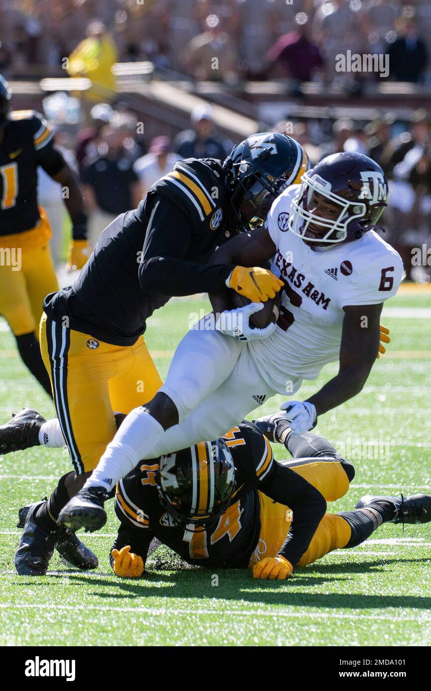 Texas A&M running back Devon Achane center, is tackled by Missouri's Jaylon Carlies, left, and ...