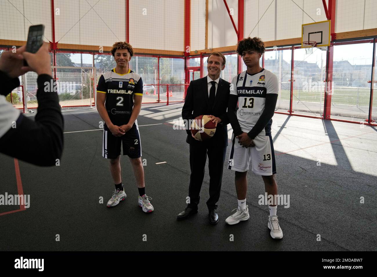 French President Emmanuel Macron poses with youths at a basketball ...