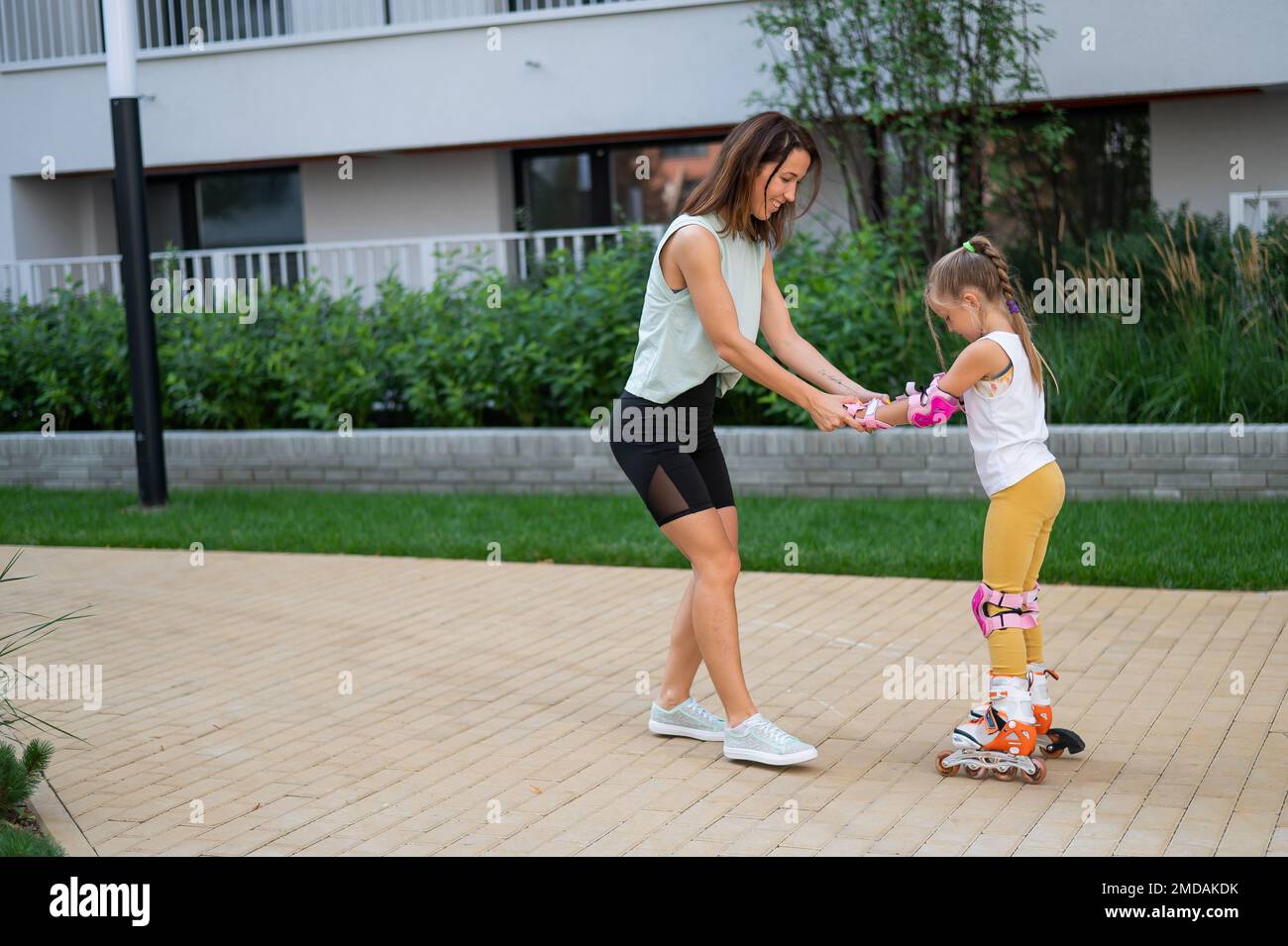 Mother helps daughter learn to roller skate Stock Photo - Alamy