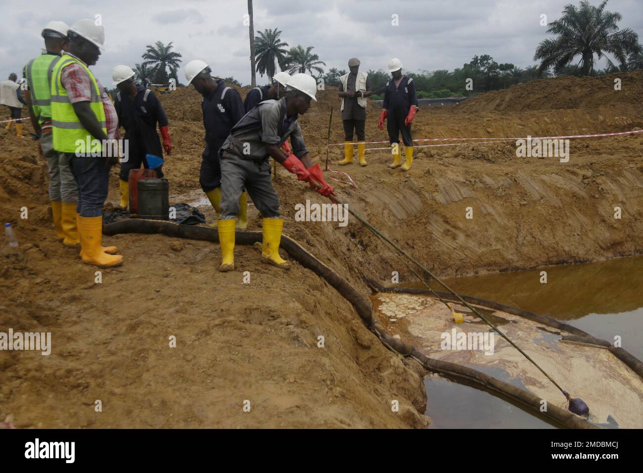 Workers use the boom method to separate water from oil, during an oil ...