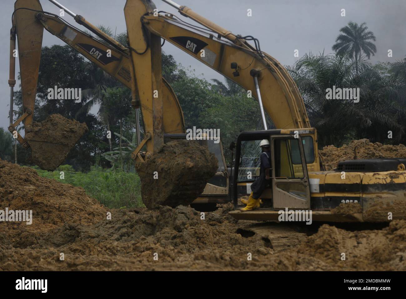 Workers use caterpillars to excavate contaminated soil caused by oil ...