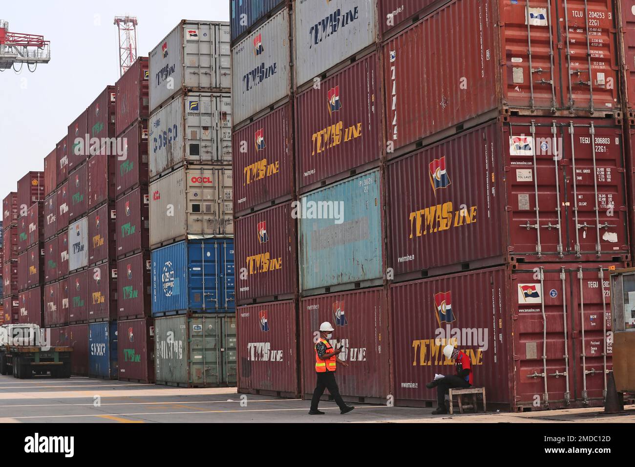 Dock workers pass containers at the terminal of Indonesia Port ...