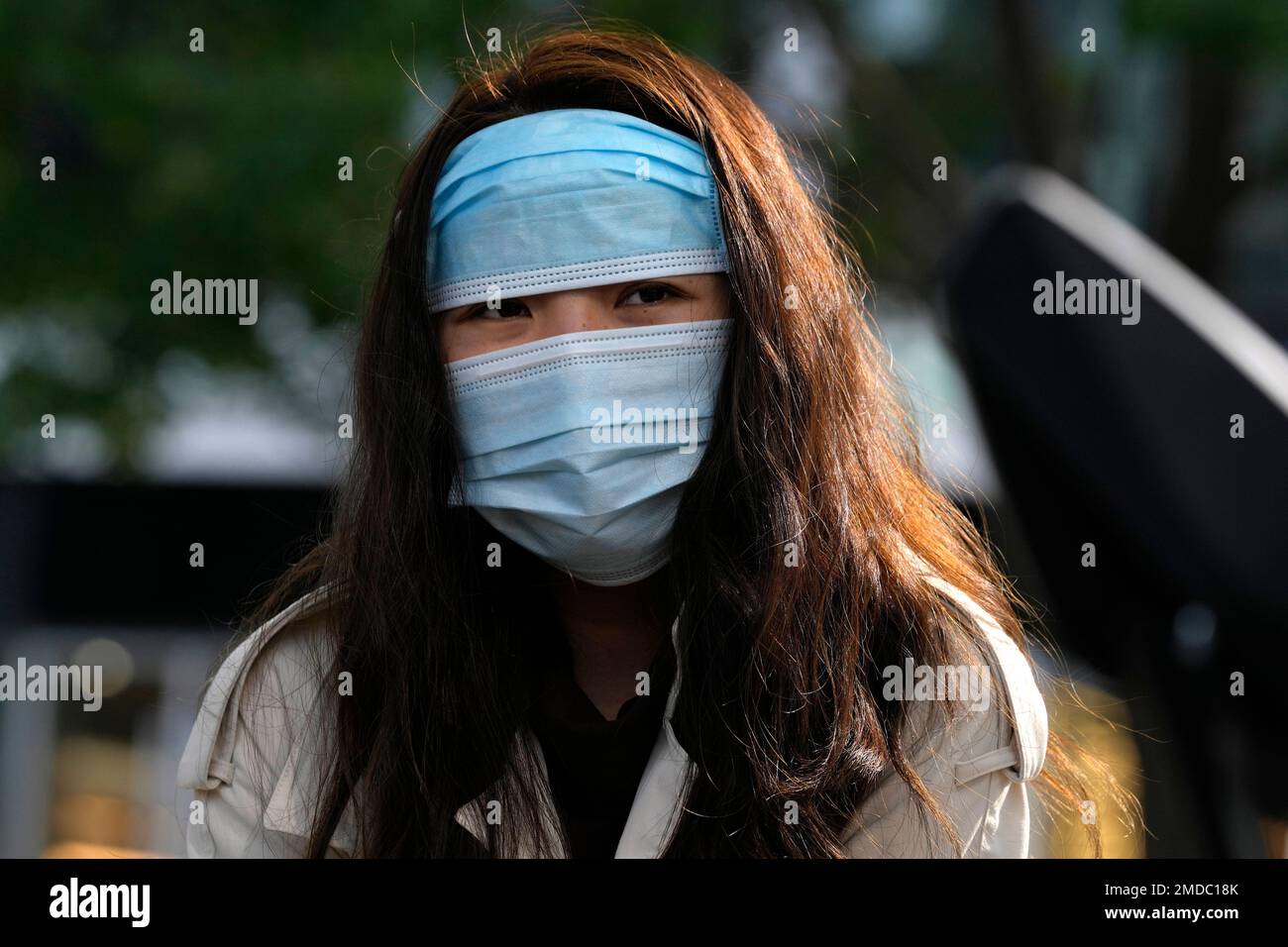 A woman wears two masks on her face on the streets of Beijing, China ...
