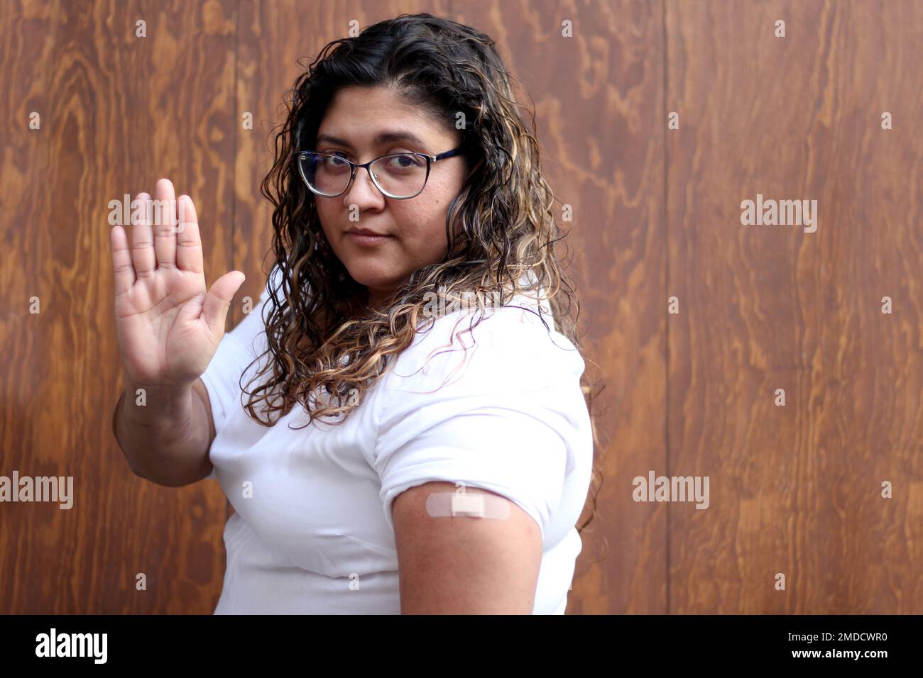 Latin adult woman with white blouse wavy hair and glasses shows her arm ...