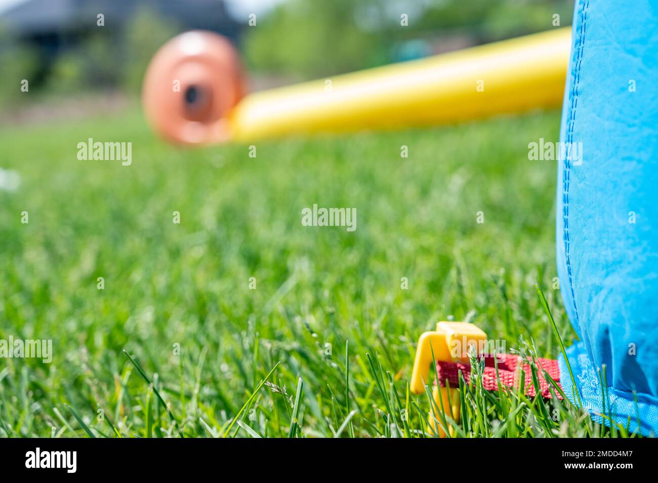 Focus on grass with blurred bouncy house stake pinned into turf Stock ...