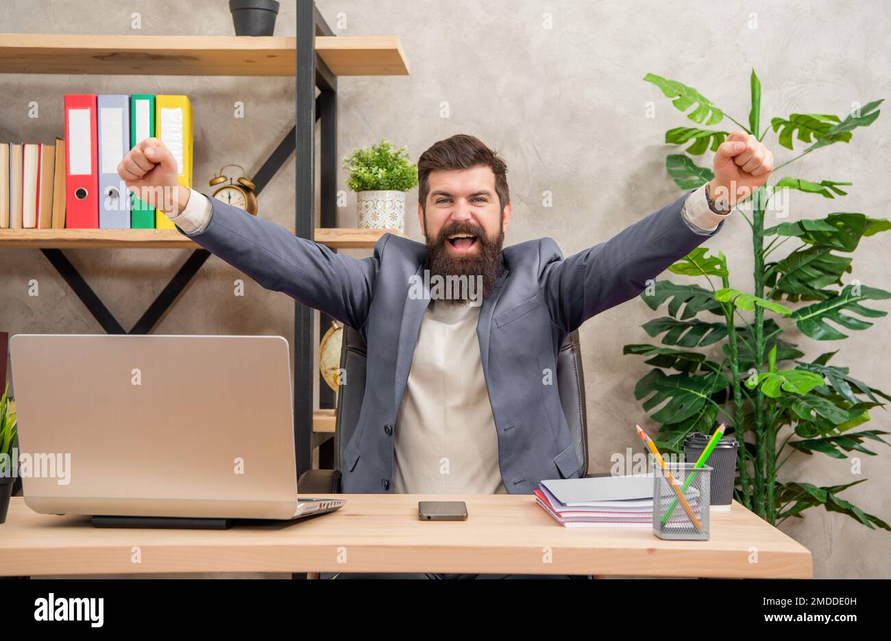Happy businessman making winning gesture working at office desk, win ...