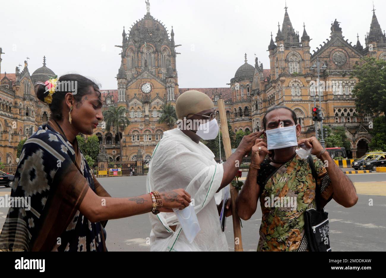 An Indian man, center, dressed as Mahatma Gandhi distributes face masks ...