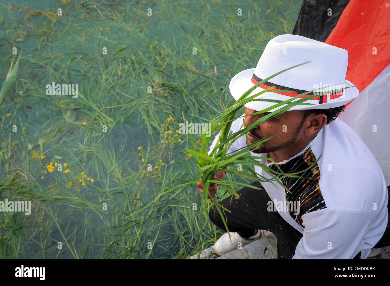 Oromos throw grass and flowers into a pool of water as they celebrate ...