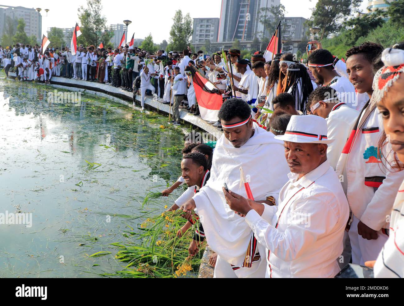 Oromos throw grass and flowers into a pool of water as they celebrate ...