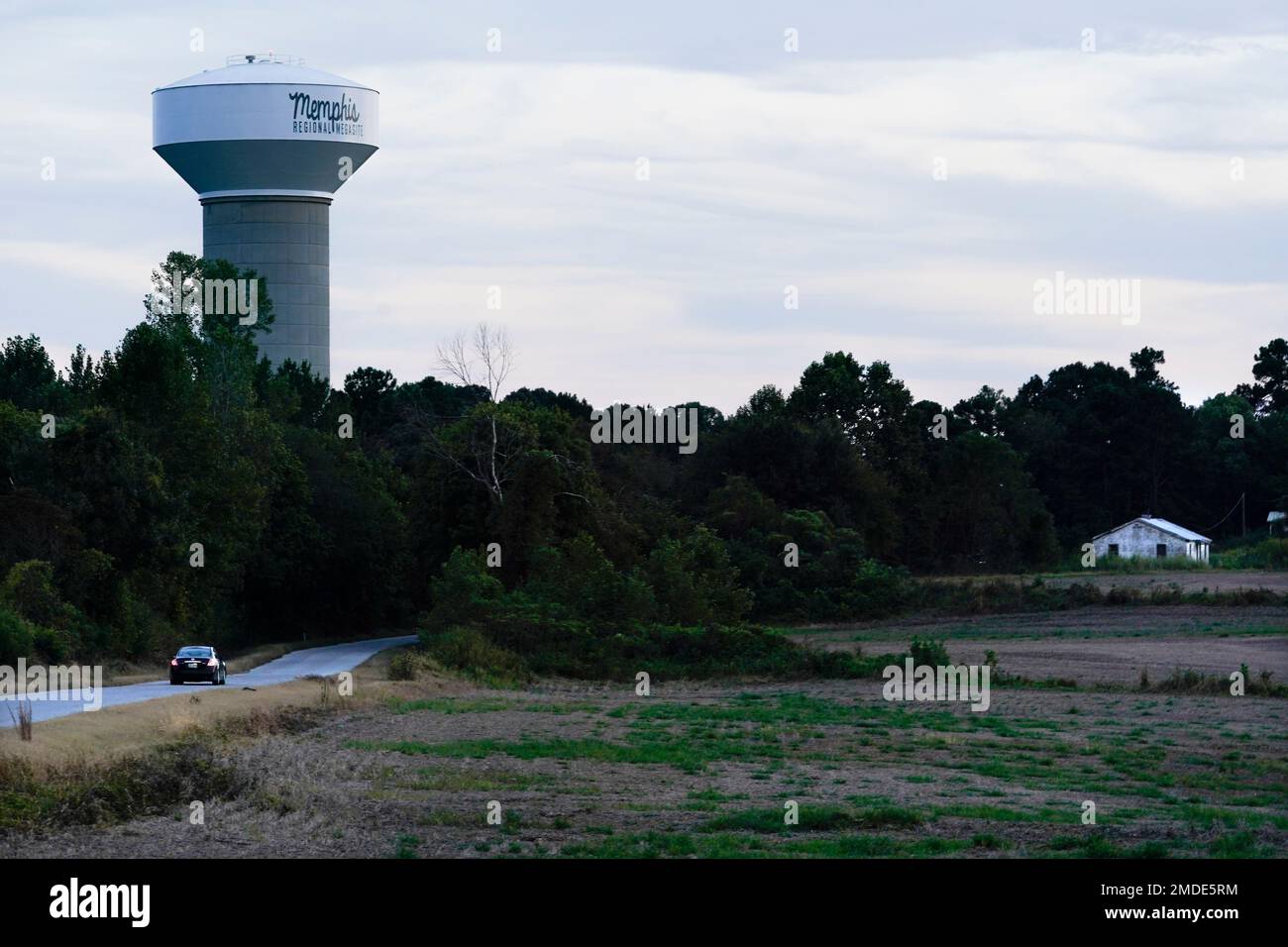 A truck drives down a rural road near a water tower marking the ...