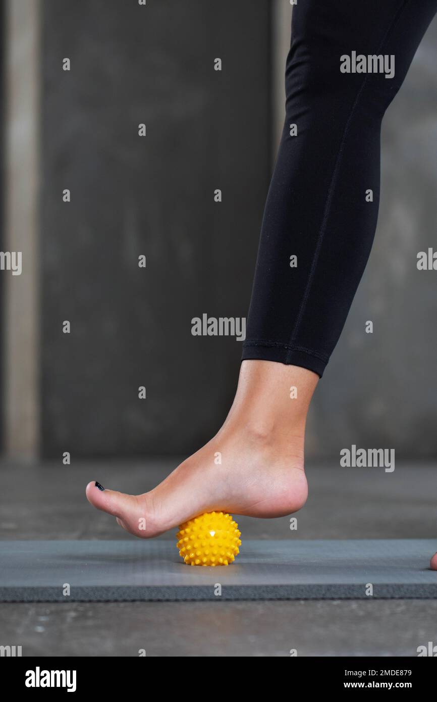 A woman does self-massage of the feet with a prickly ball, relaxation ...