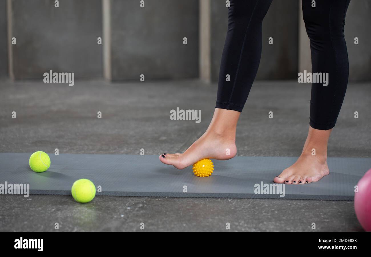 A woman does self-massage of the feet with a prickly ball, relaxation ...