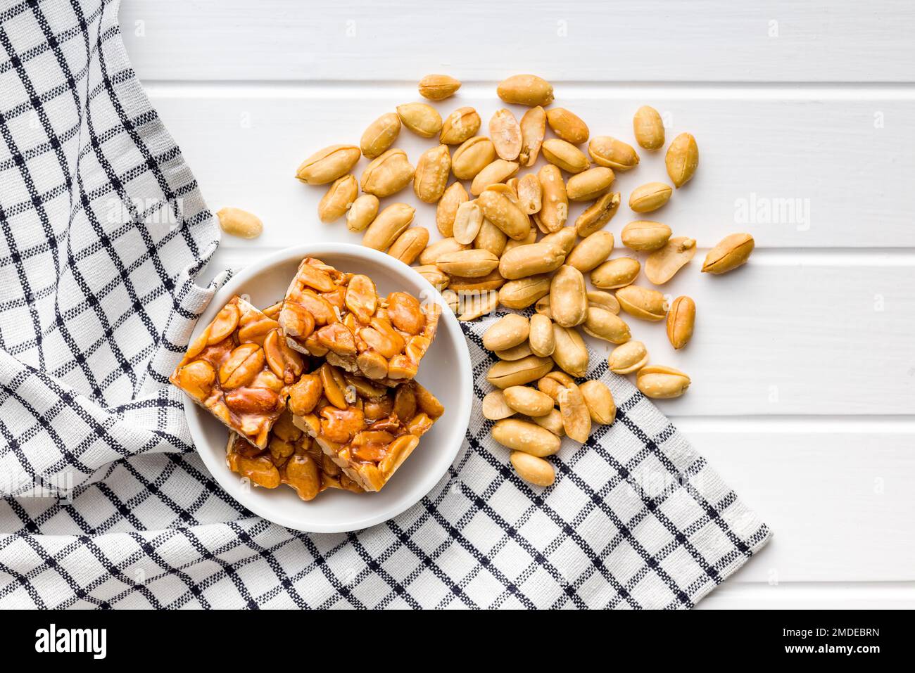 Sweet peanut brittle. Tasty peanuts in caramel on the checkered napkin ...