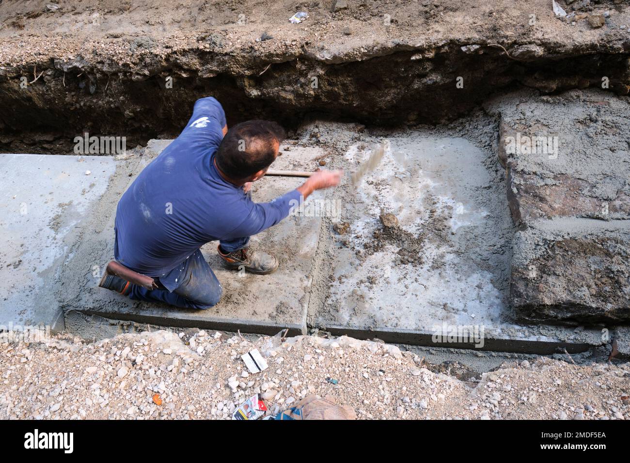 A repairman working on pipes, sewer, utilities in an open trench of the ...