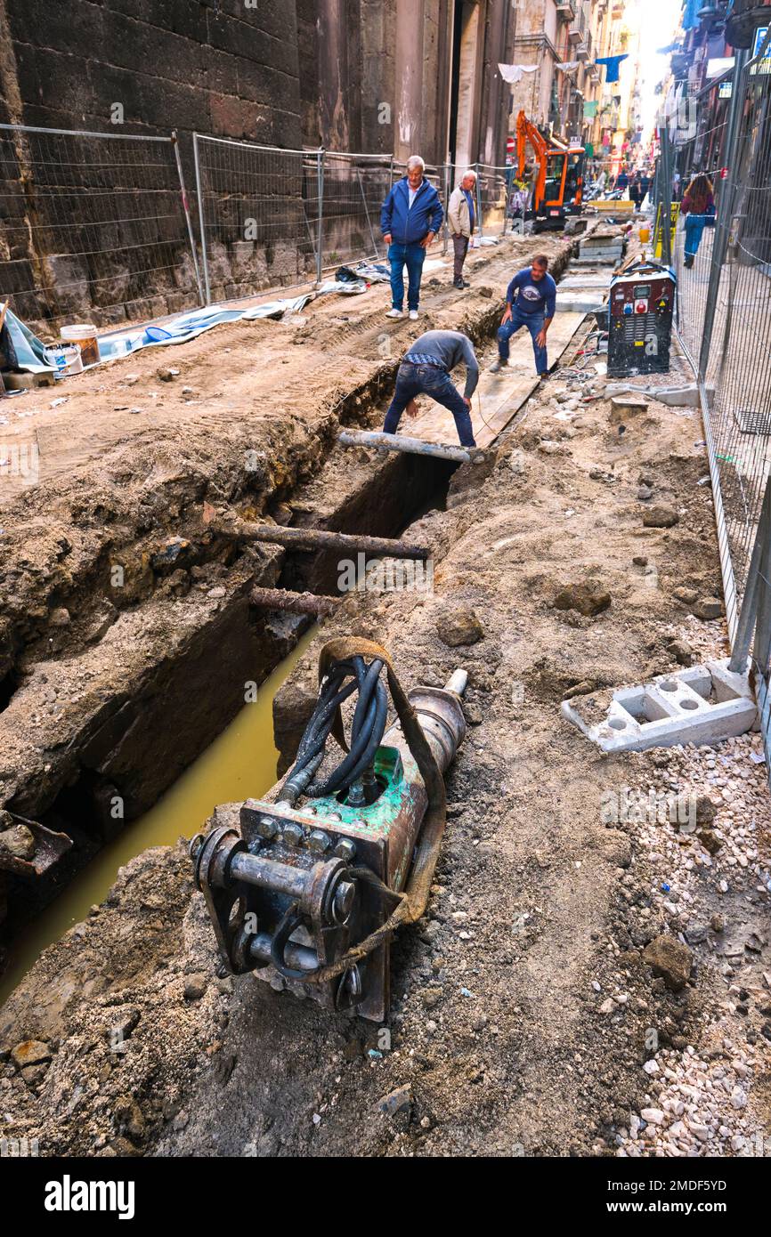 Repairmen working on pipes, sewer, utilities in an open trench of the ...