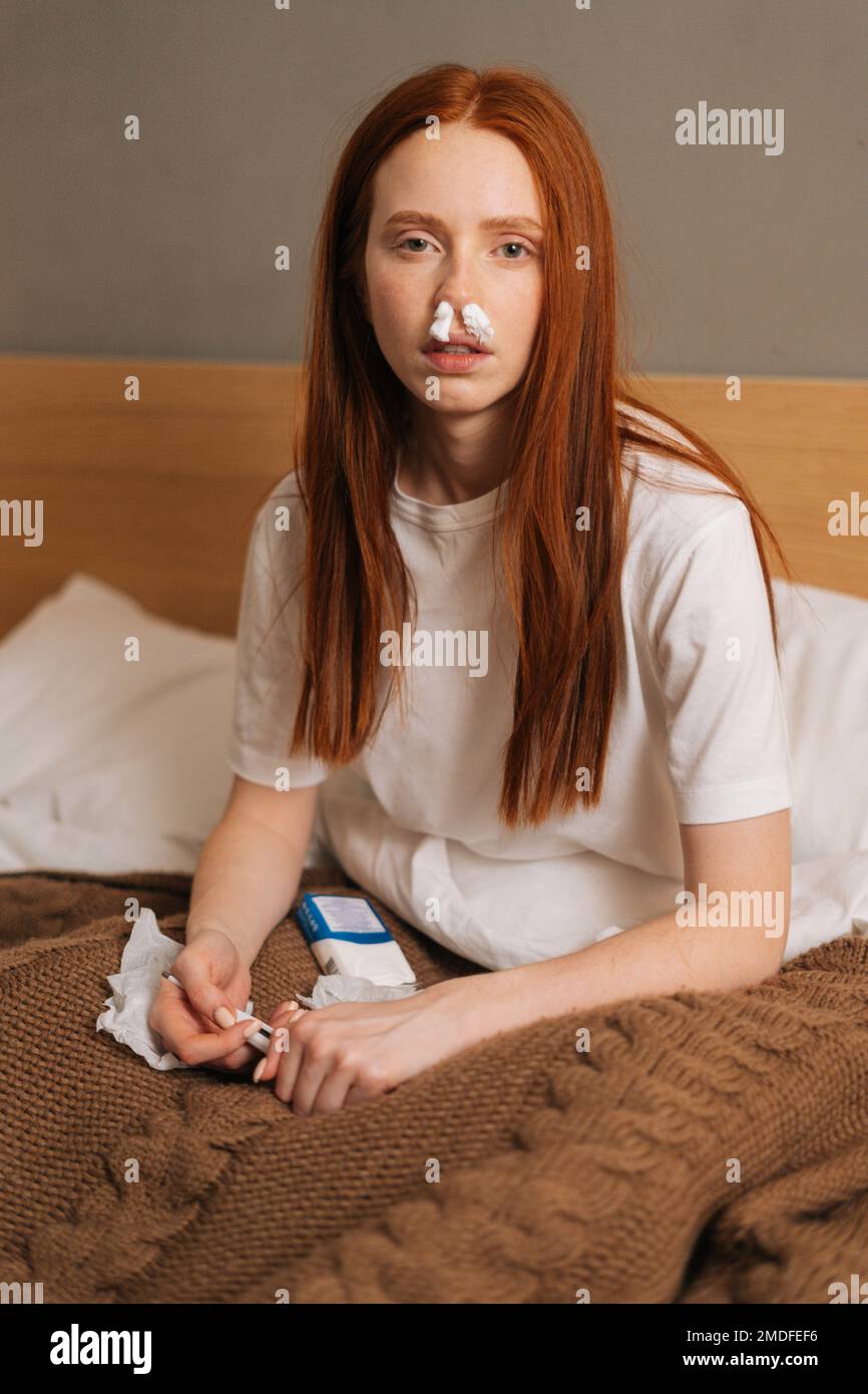 Vertical portrait of ill young woman suffering from runny nose disease ...