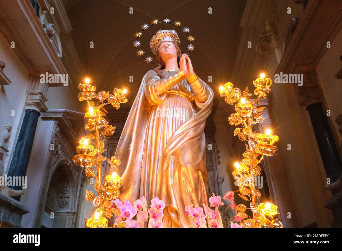 A statue, icon, relic of the Virgin Mary, hands praying, lit halo and ...